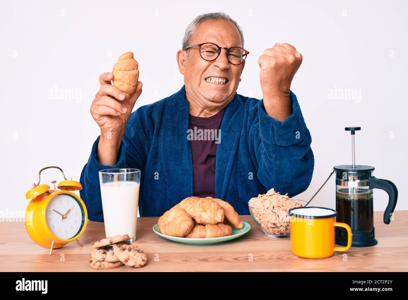 Senior handsome man with gray hair sitting on the table eating ...