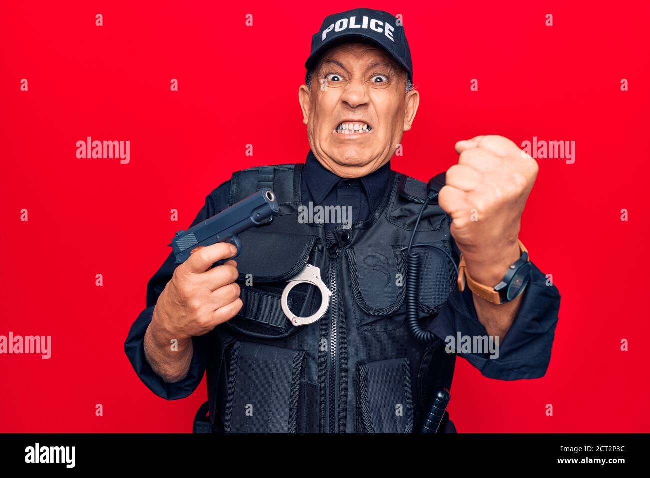Senior man with grey hair wearing police uniform holding gun annoyed ...
