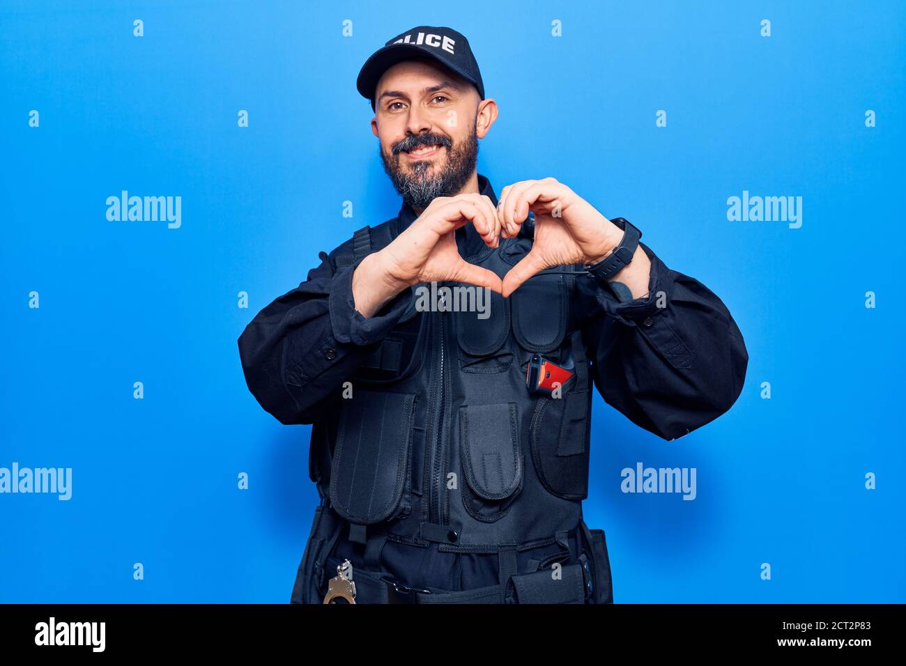 Young handsome man wearing police uniform smiling in love showing heart ...