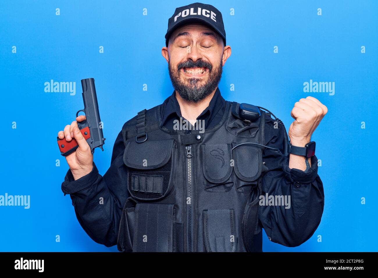 Young handsome man wearing police uniform holding gun screaming proud ...