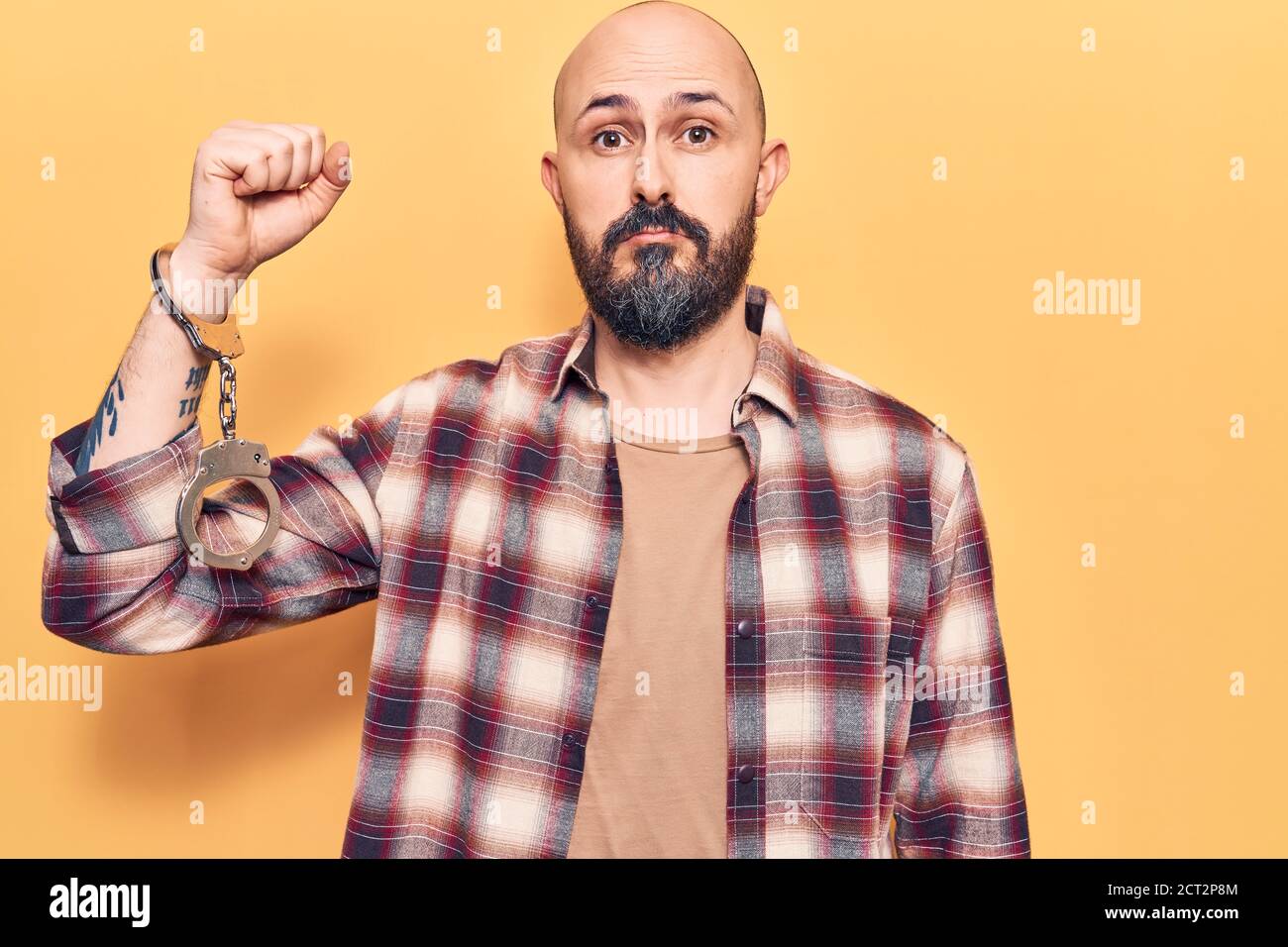 Young handsome man wearing prisoner handcuffs thinking attitude and ...