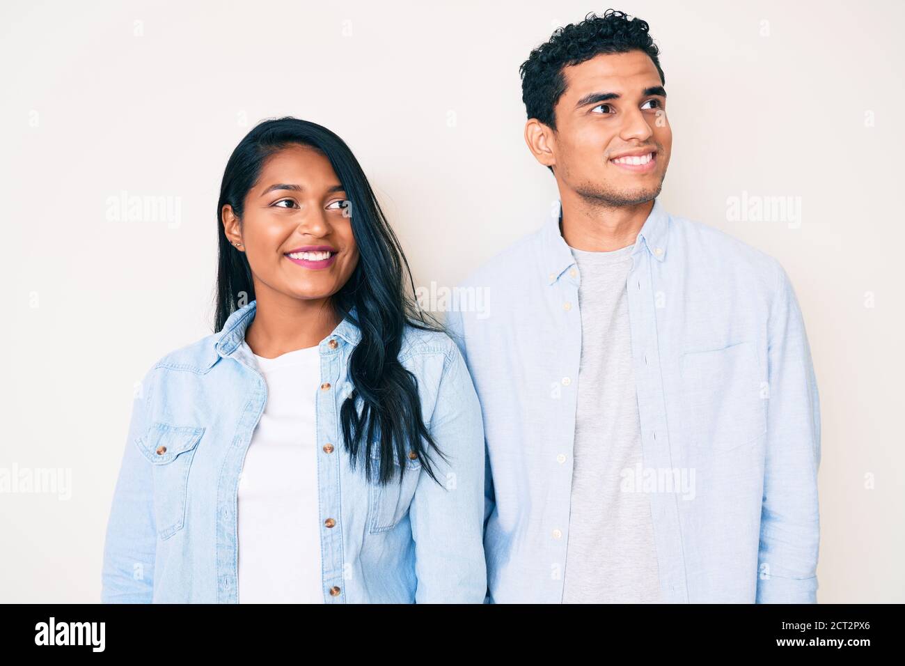 Beautiful latin young couple wearing casual clothes looking away to ...