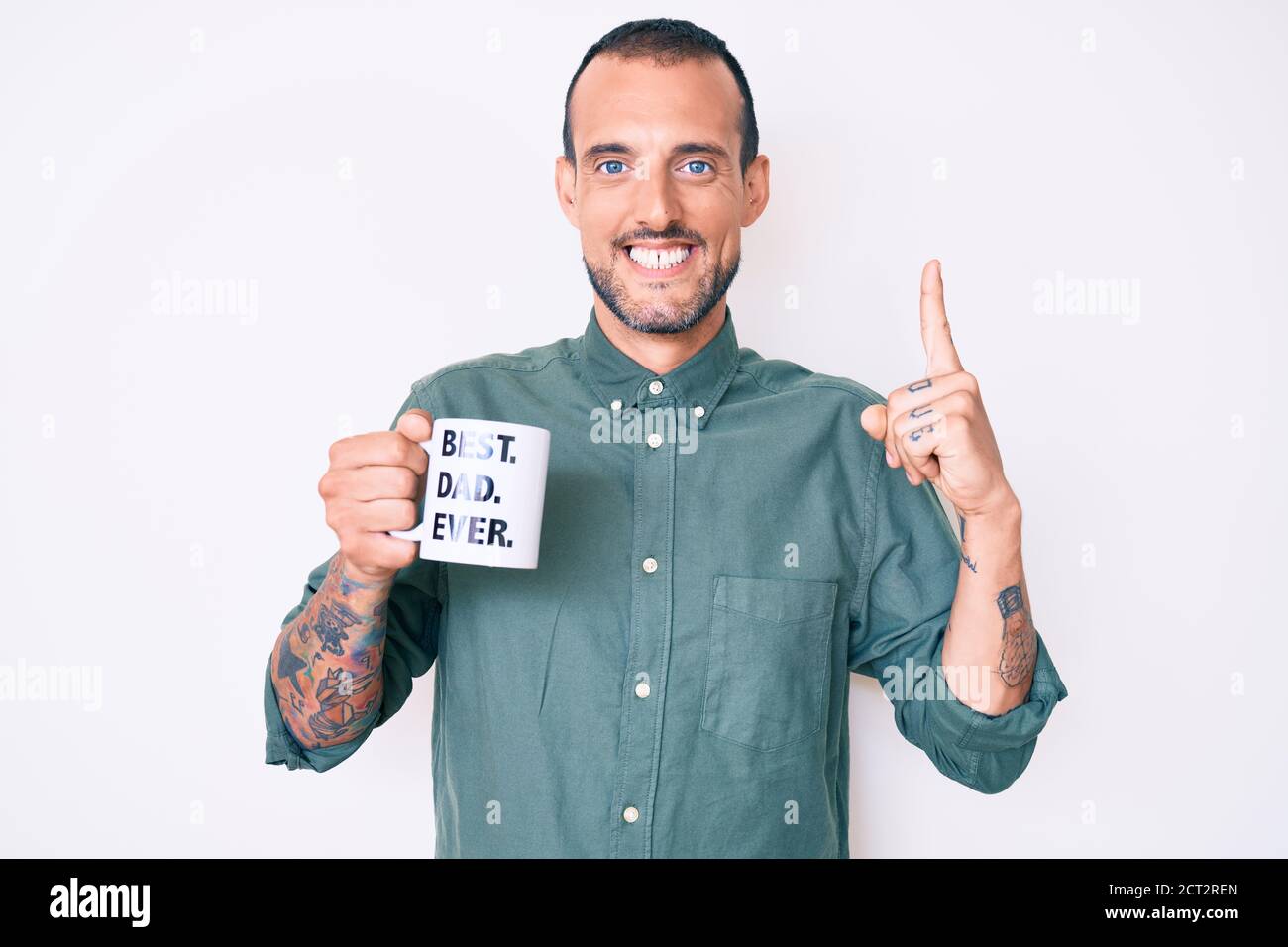 Young handsome man with tattoo drinking mug of coffe with best dad ever ...