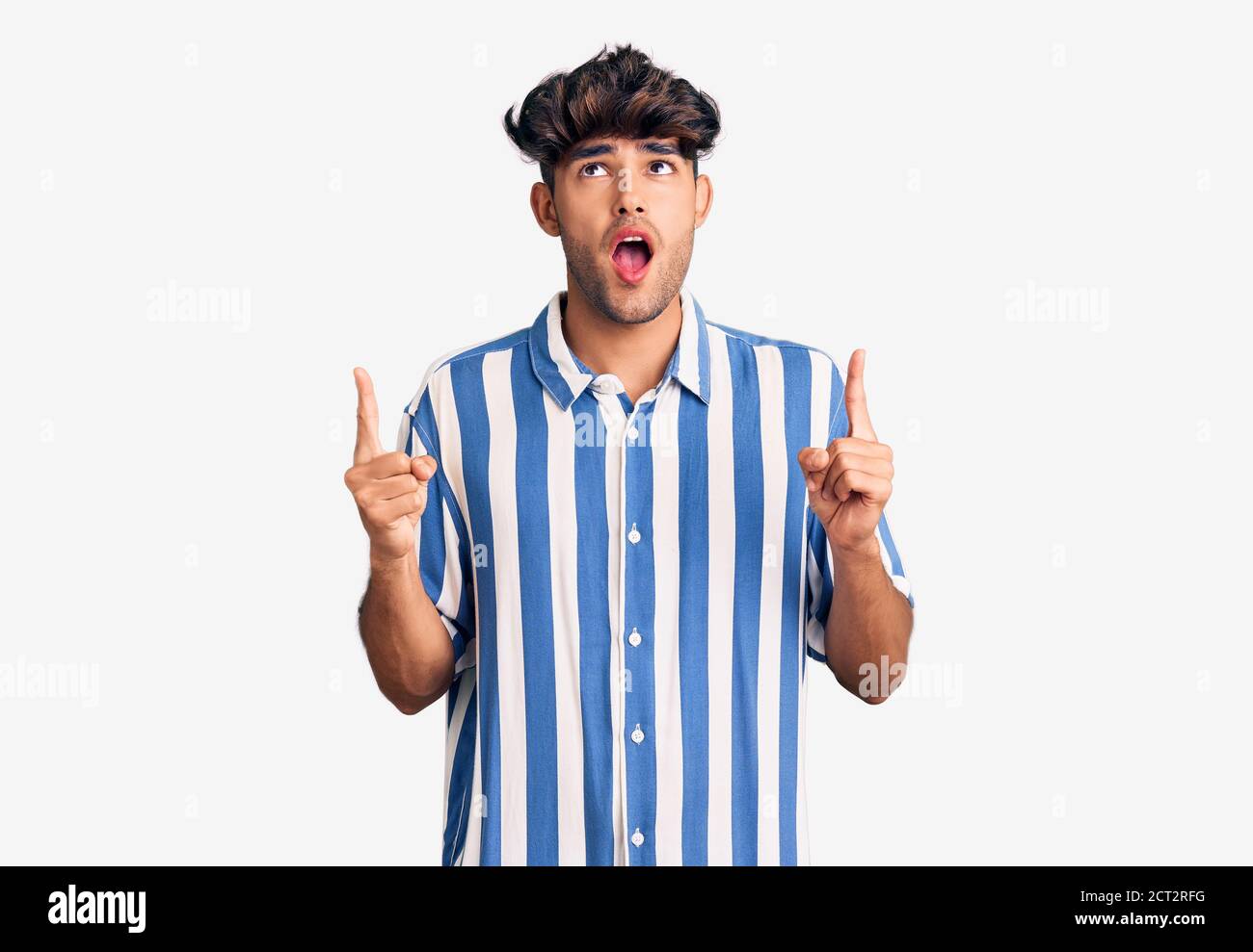 Young hispanic man wearing casual clothes amazed and surprised looking ...