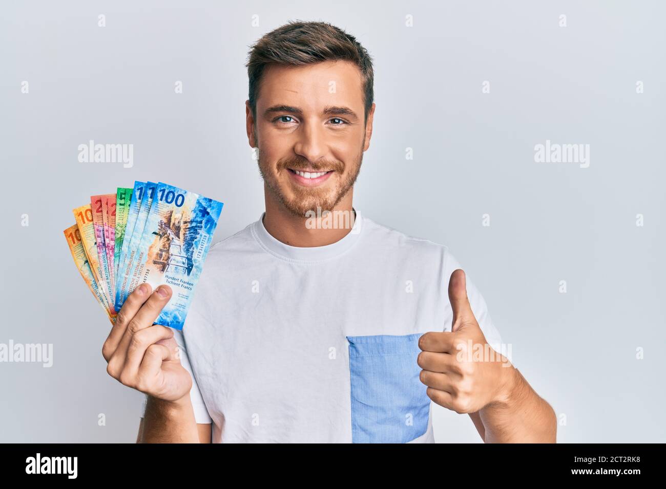 Handsome caucasian man holding swiss franc banknotes smiling happy and ...