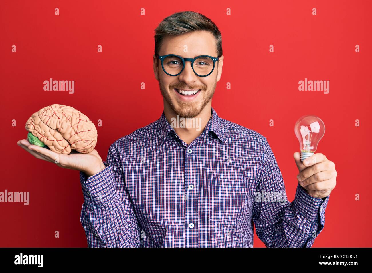 Handsome caucasian man holding brain and lightbulb for inspiration and ...