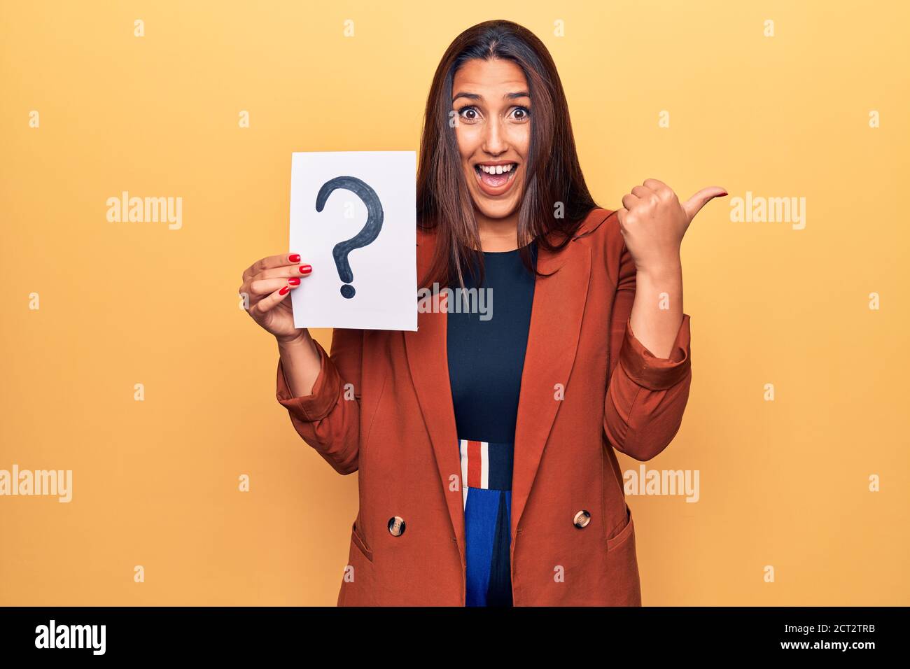 Young beautiful brunette woman holding paper with question mark ...