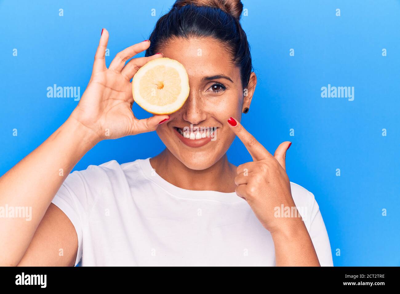 Young beautiful brunette woman holding slice of lemon smiling happy ...
