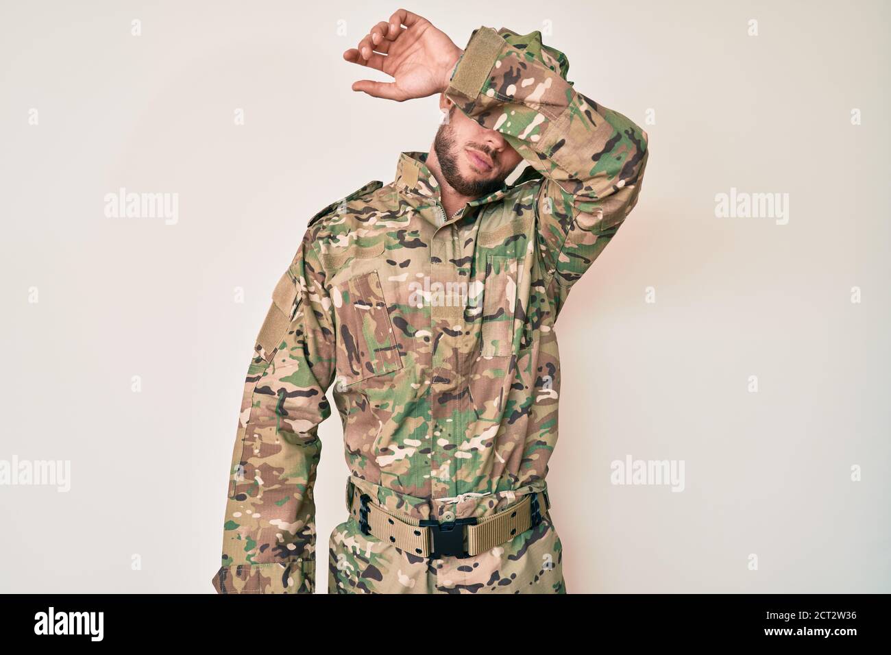 Young caucasian man wearing camouflage army uniform covering eyes with ...