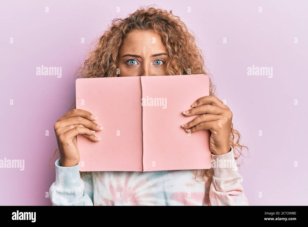 Beautiful caucasian teenager girl reading a book covering face puffing ...