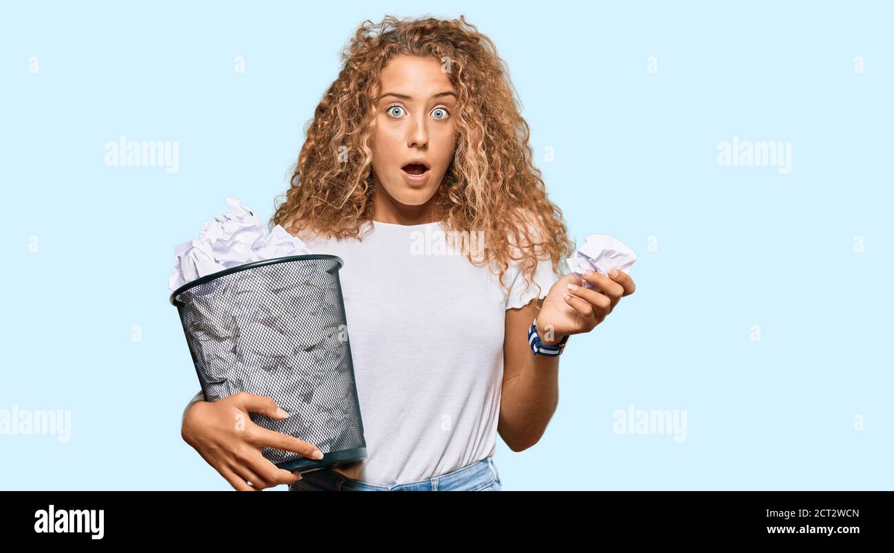 Beautiful caucasian teenager girl holding paper bin full of crumpled ...
