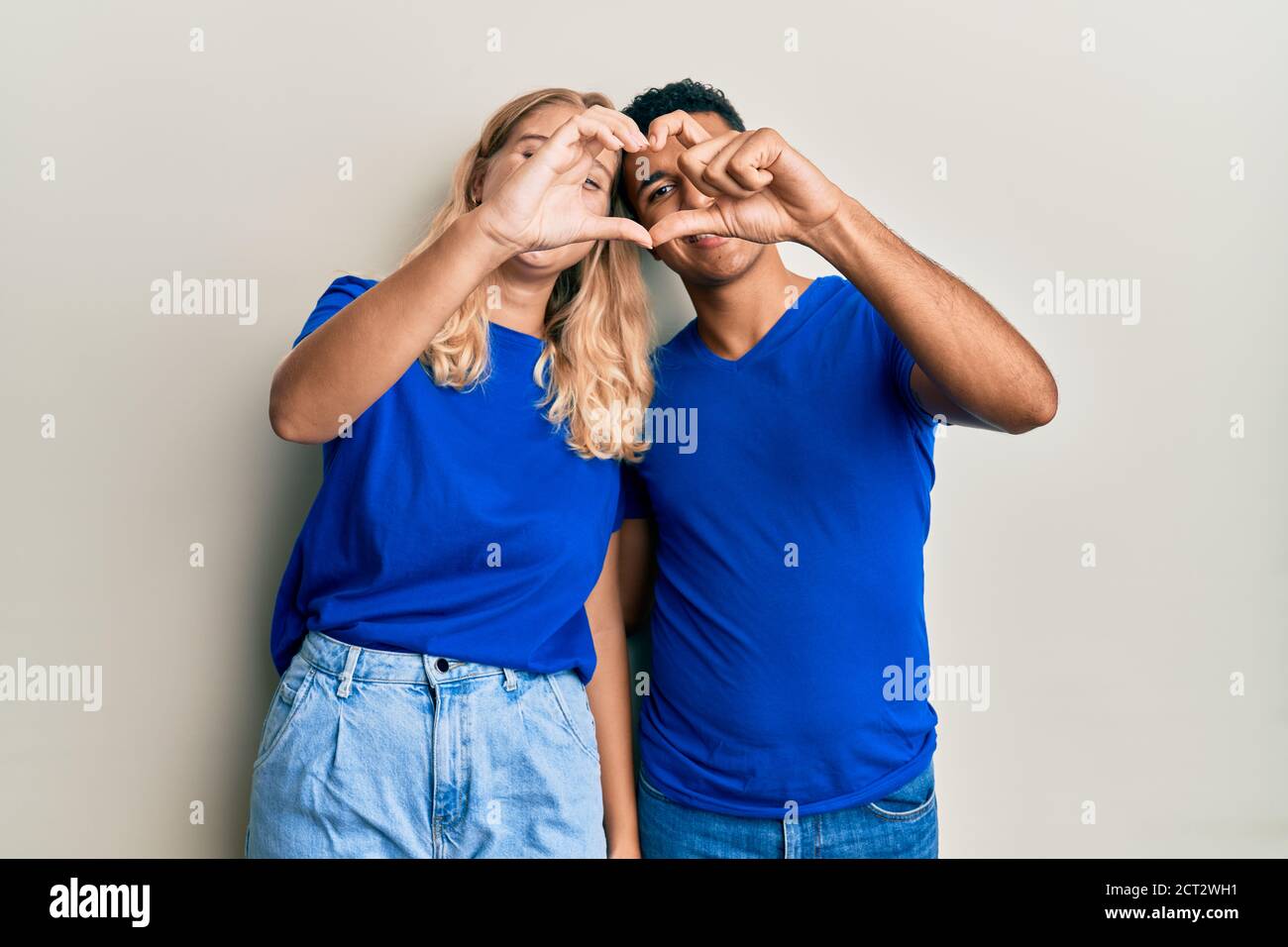 Young Interracial Couple Wearing Casual Clothes Doing Heart Shape With