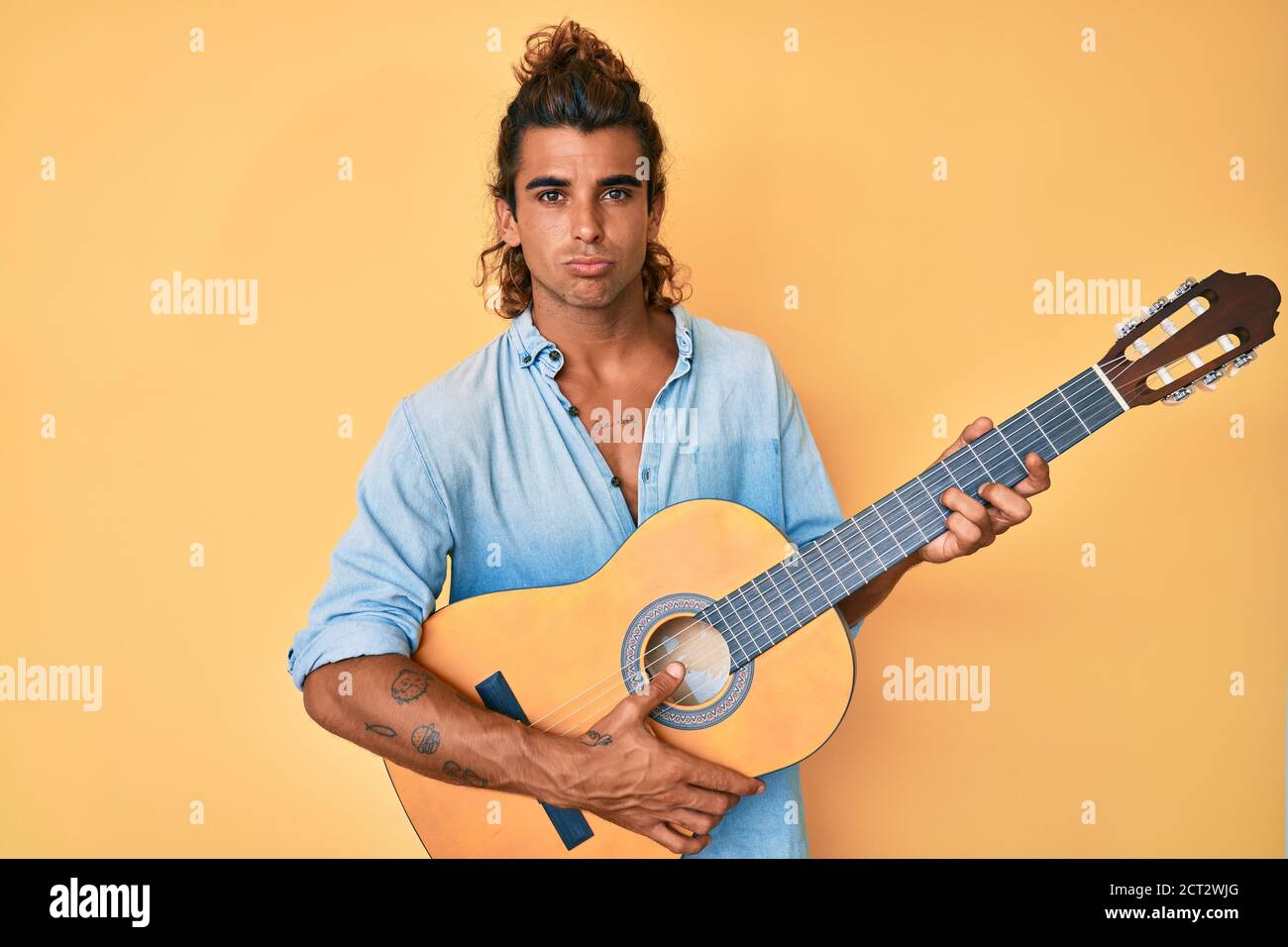 Young hispanic man playing classical guitar depressed and worry for ...