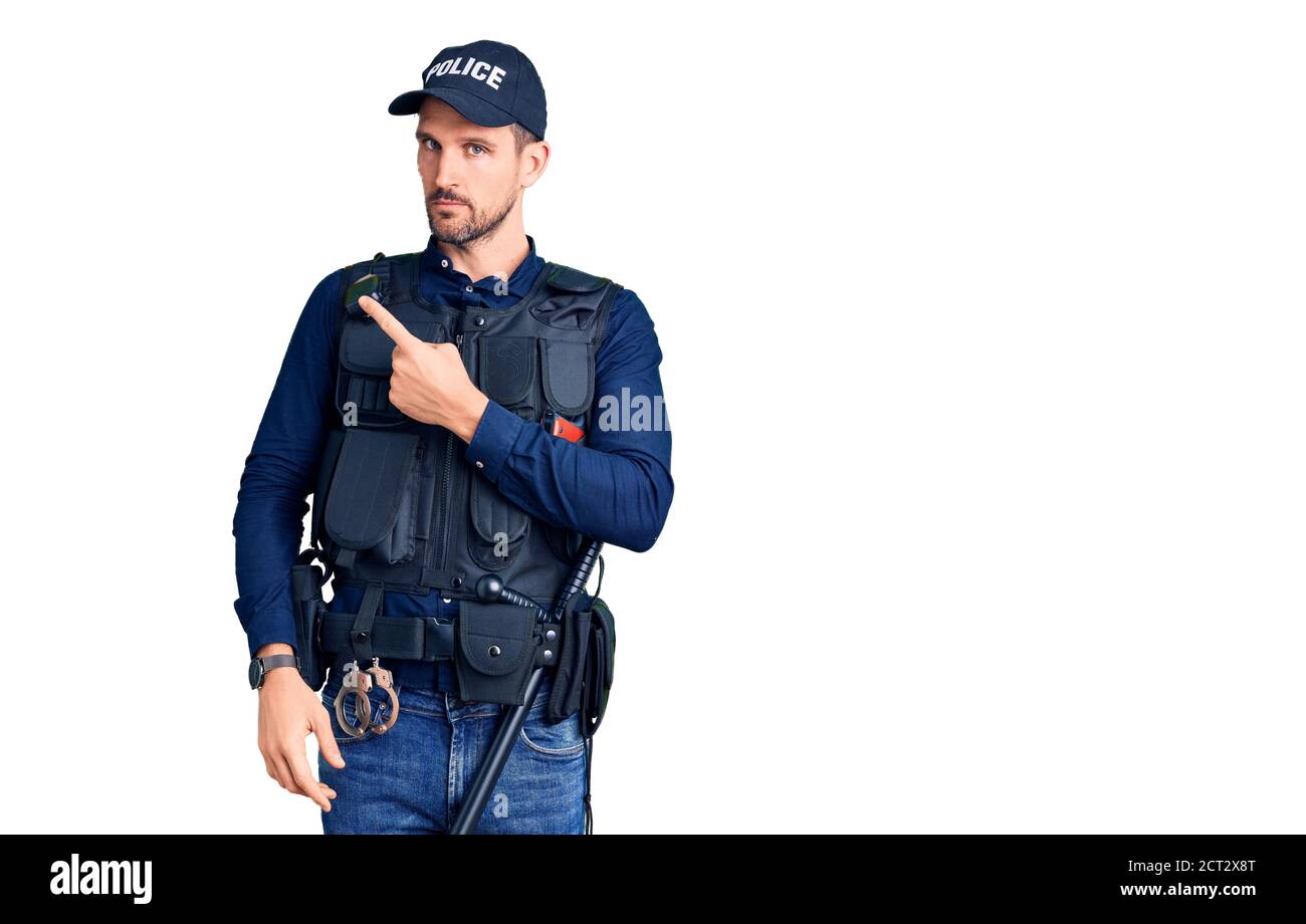 Young handsome man wearing police uniform pointing with hand finger to ...