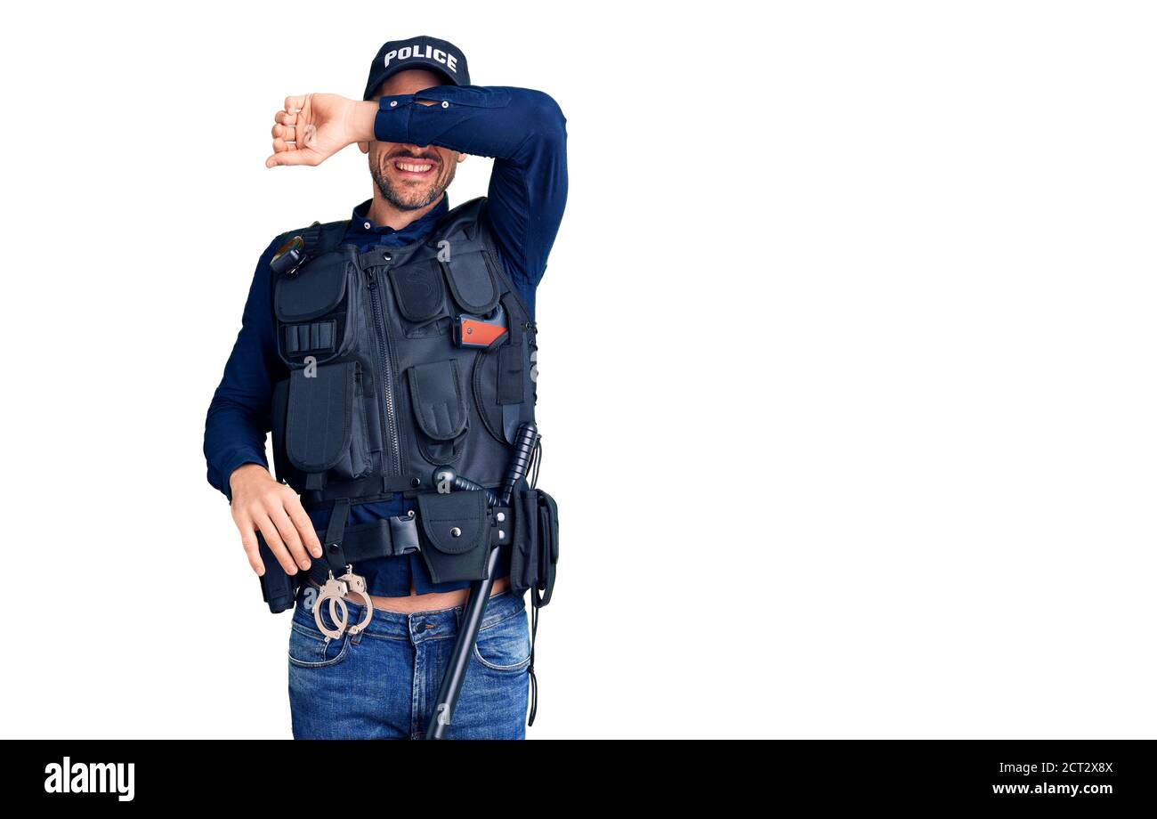 Young handsome man wearing police uniform covering eyes with arm ...