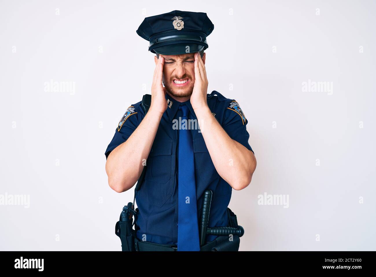 Young caucasian man wearing police uniform with hand on head, headache ...
