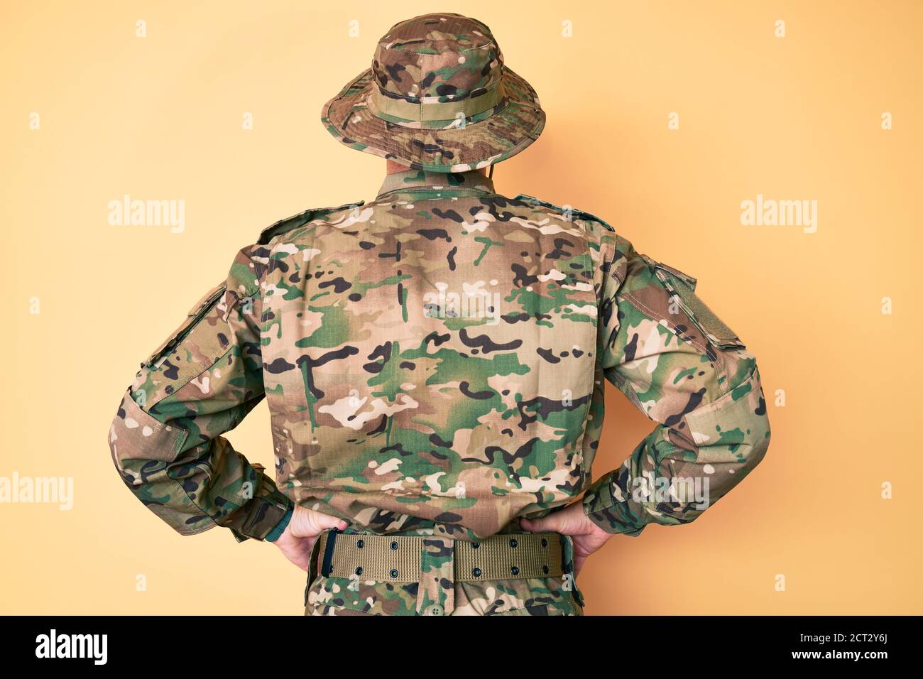 Young caucasian man wearing camouflage army uniform standing backwards ...