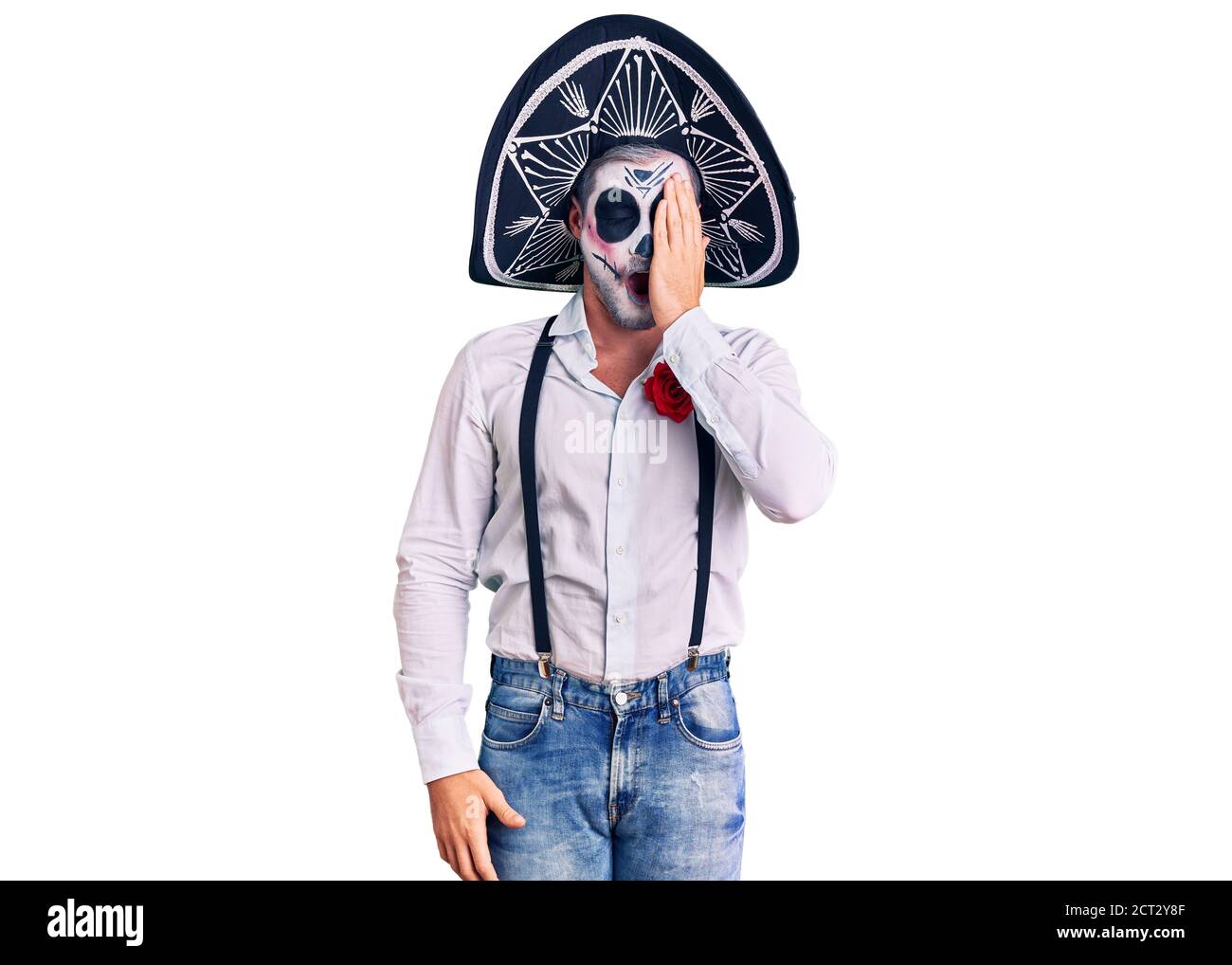Man wearing day of the dead costume over background yawning tired ...