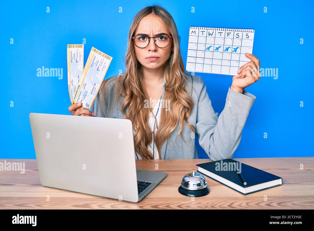 Young beautiful blonde woman holding boarding pass and travel calendar ...