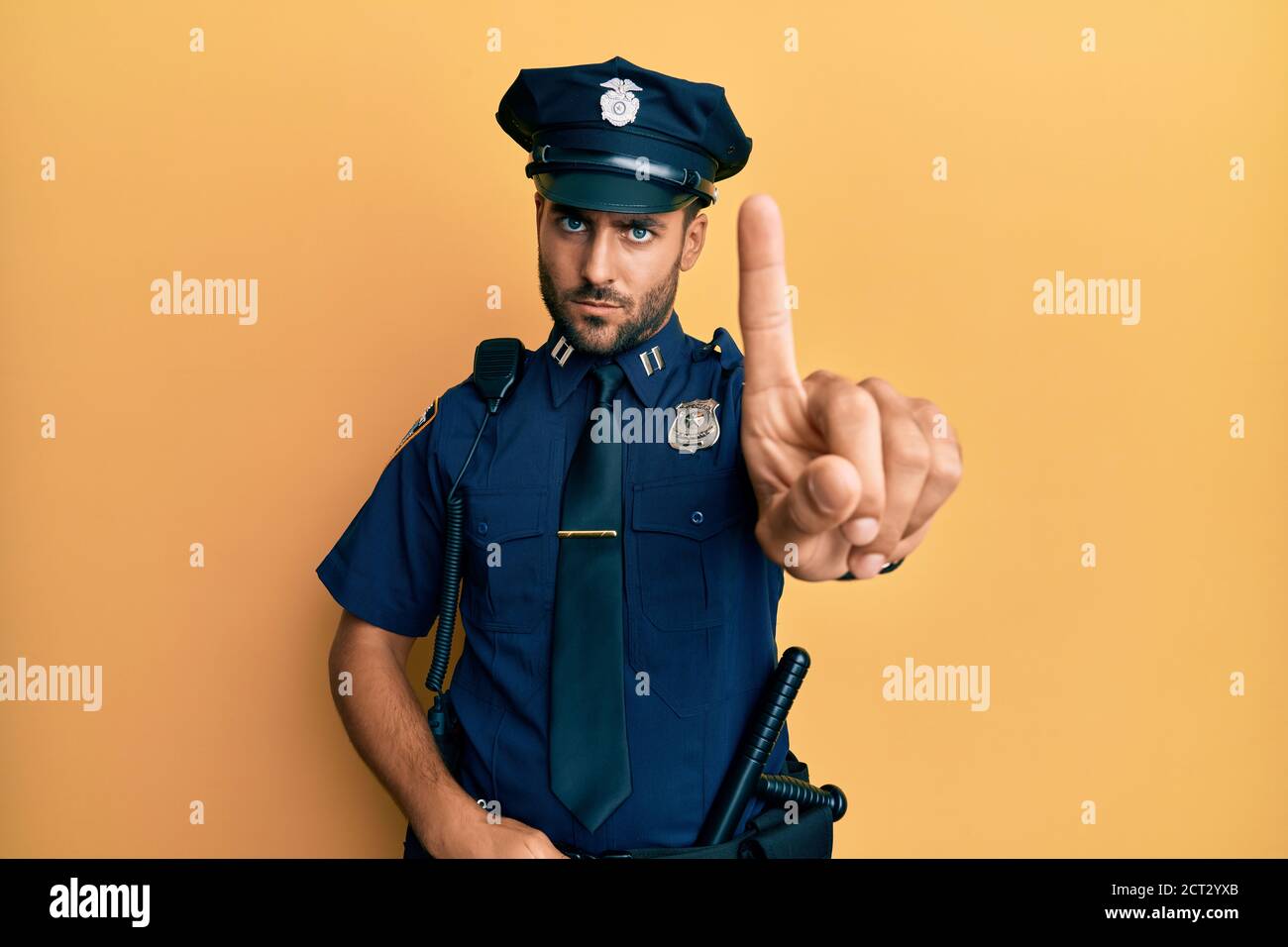 Handsome hispanic man wearing police uniform pointing with finger up ...