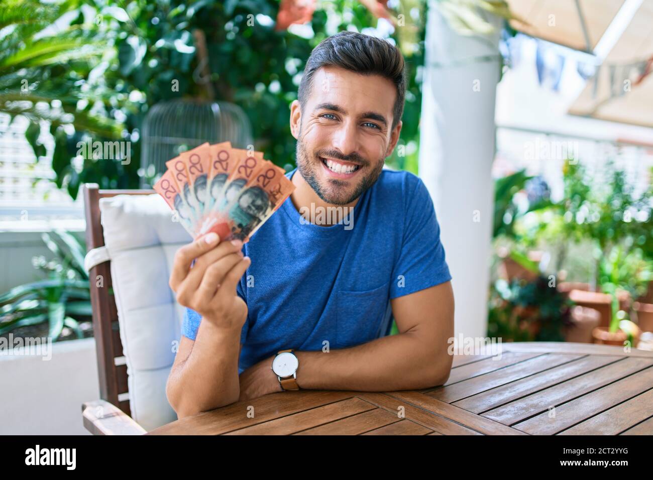 Young hispanic man smiling happy holding australian dollars banknotes ...