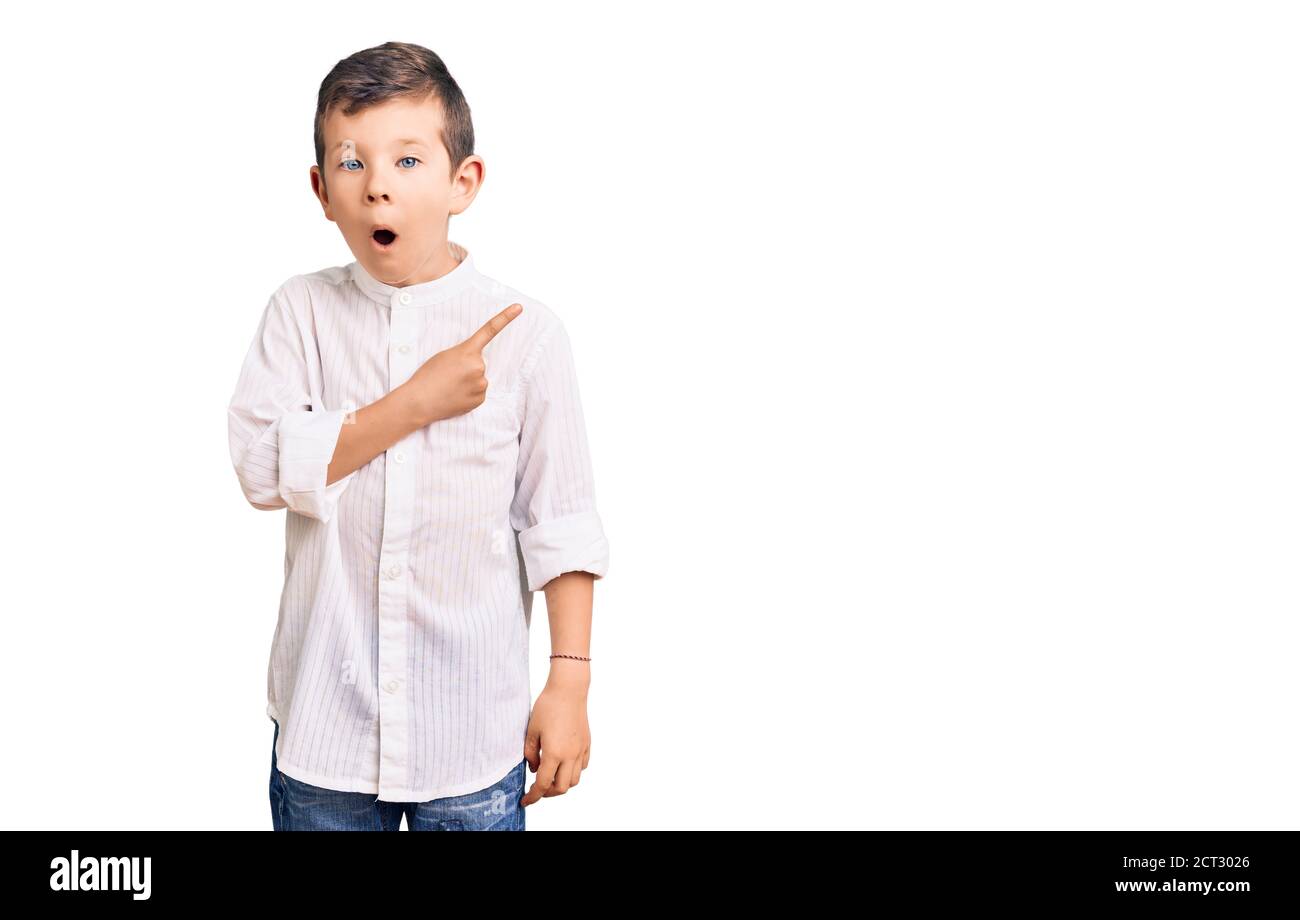 Cute blond kid wearing elegant shirt surprised pointing with finger to ...