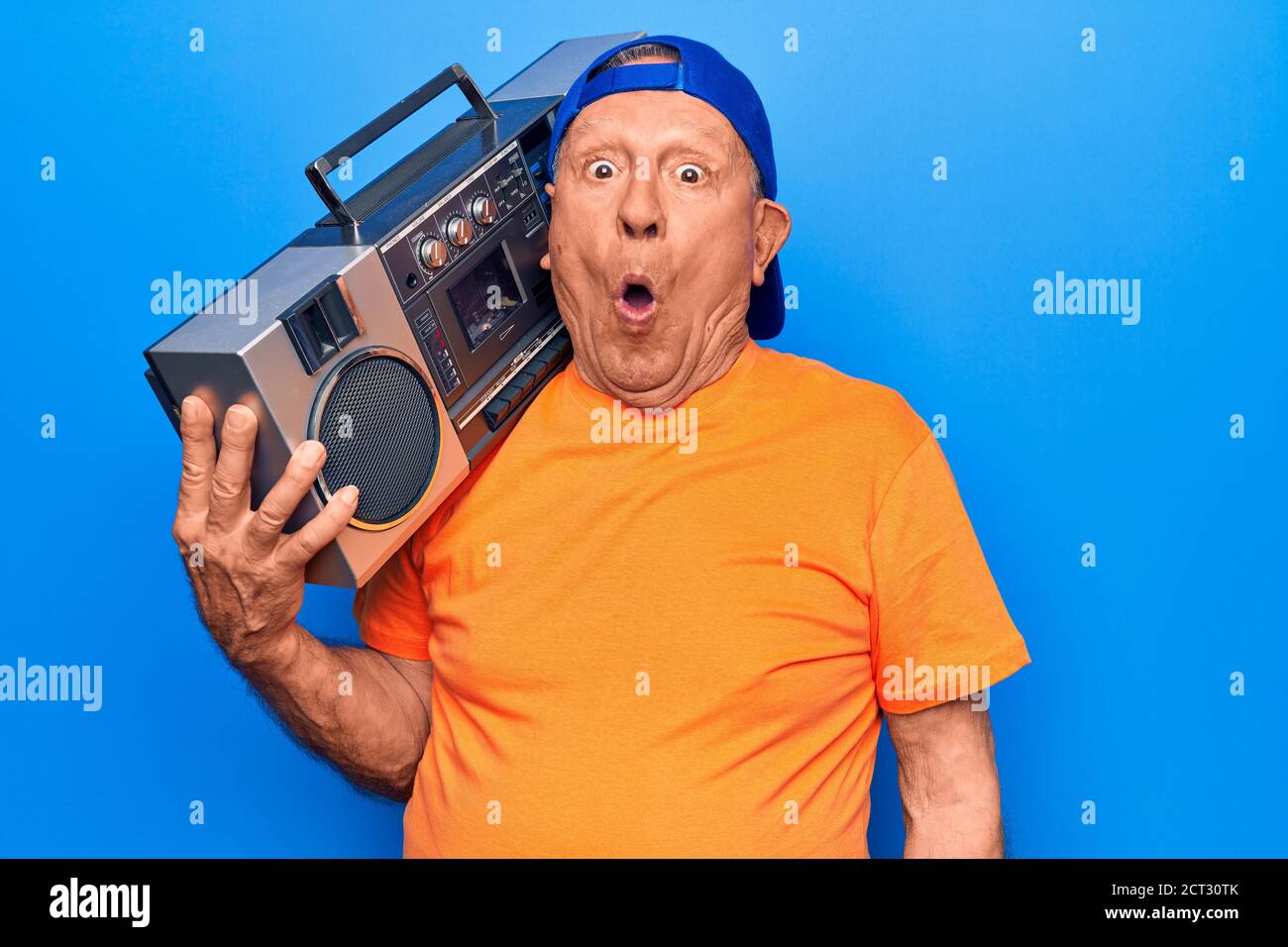 Senior modern handsome grey-haired man wearing cap listening to music ...