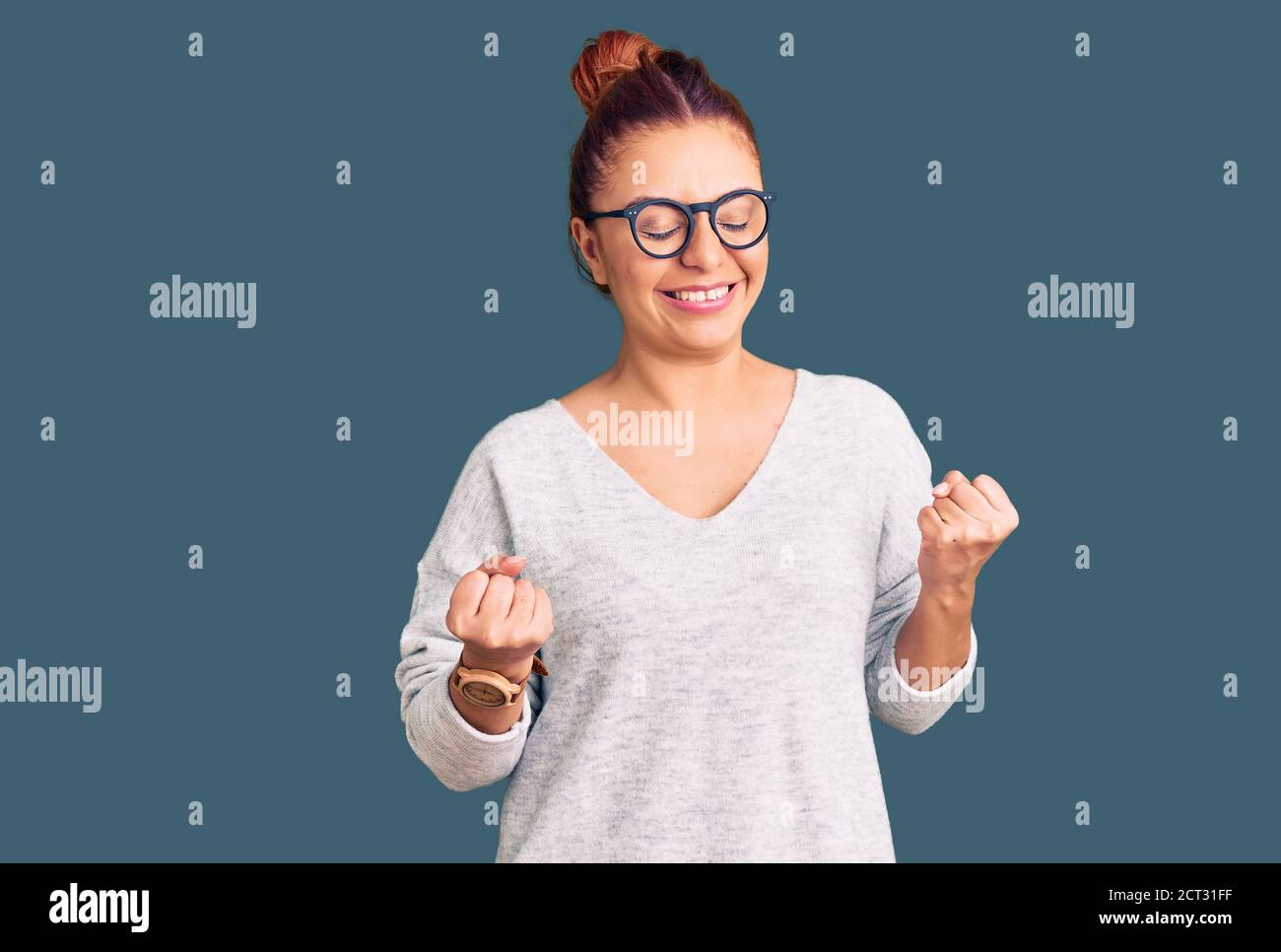 Young latin woman wearing casual clothes excited for success with arms ...