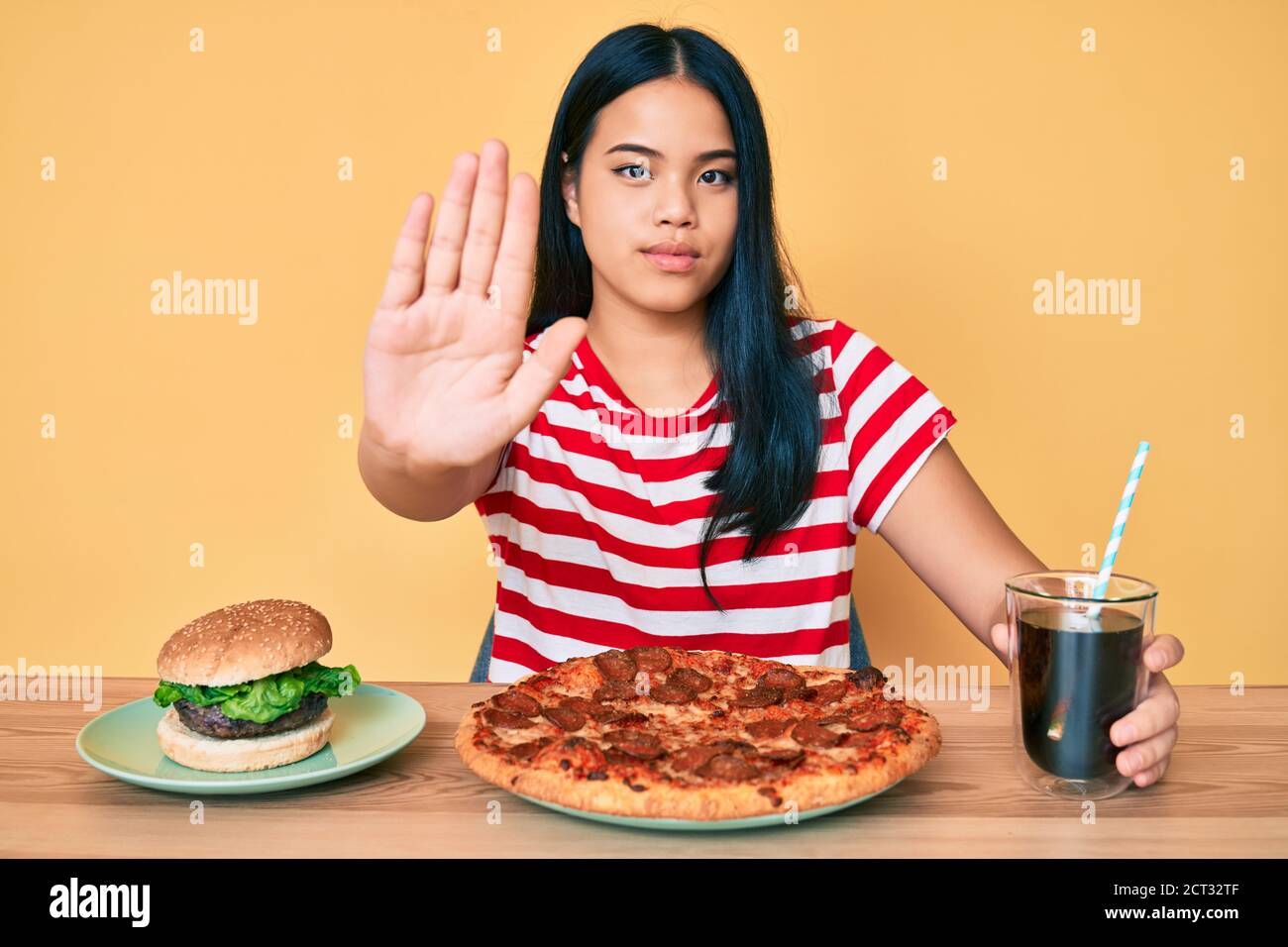 Young beautiful asian girl eating fast food pizza and burger with open ...