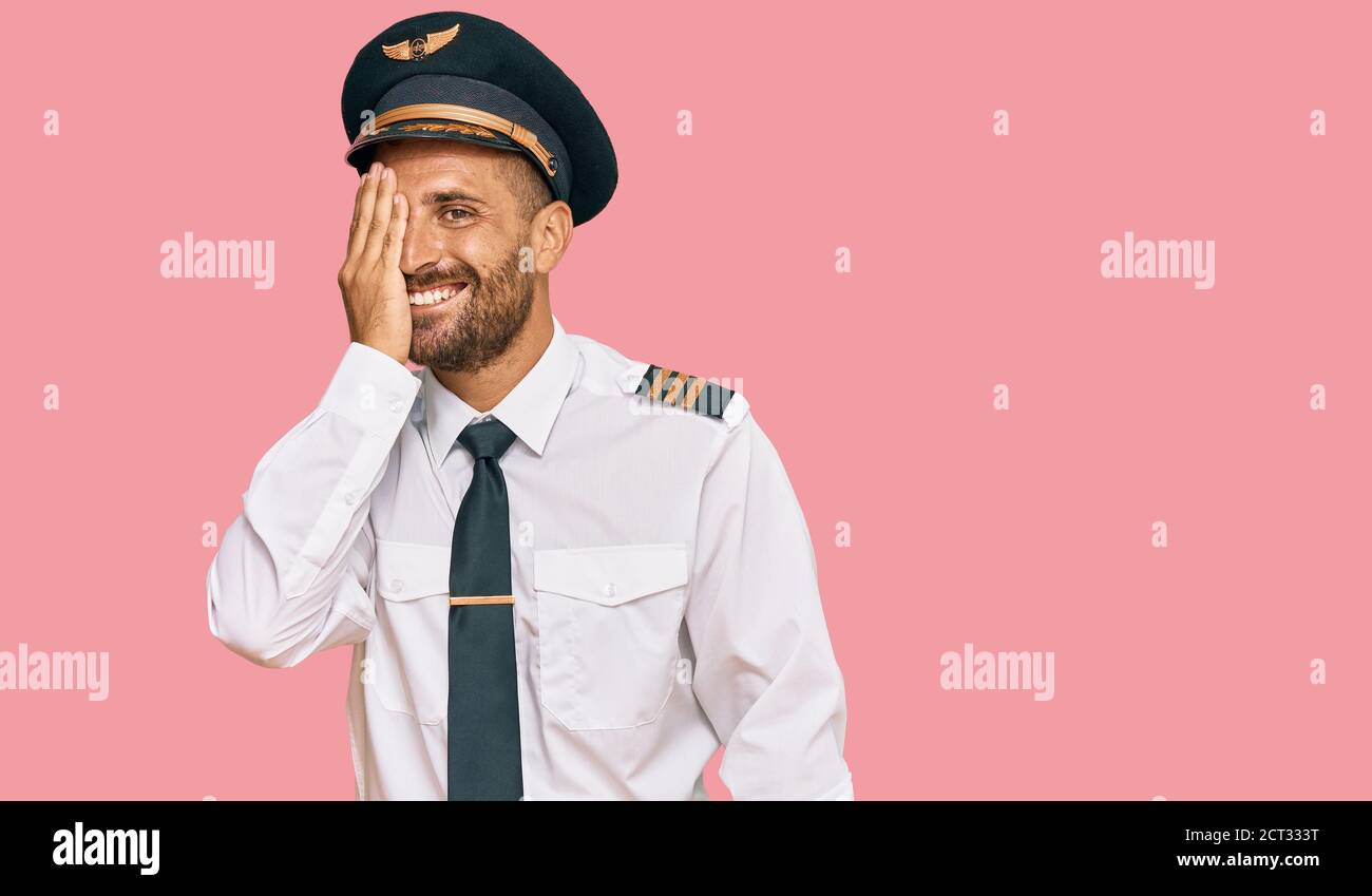 Handsome man with beard wearing airplane pilot uniform covering one eye ...