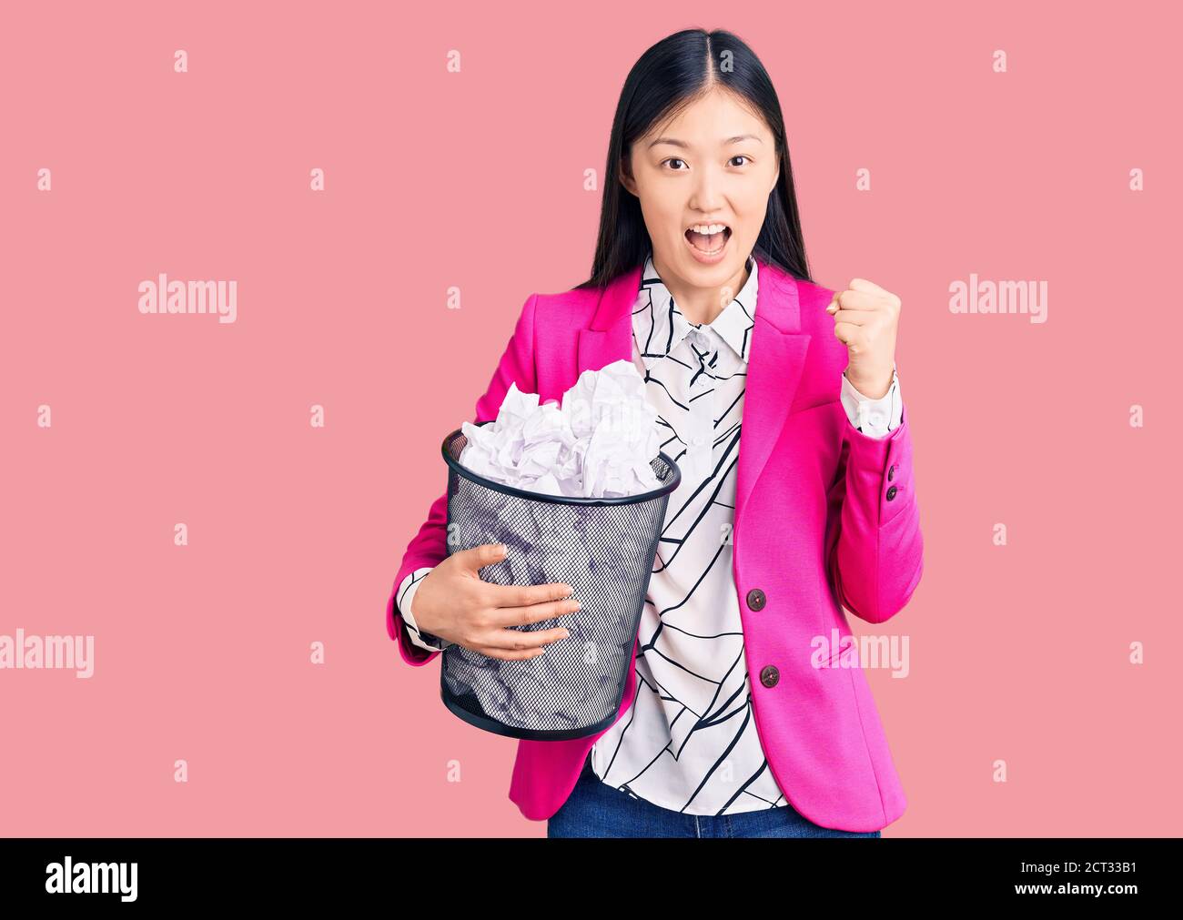 Young beautiful chinese woman holding paper bin full of crumpled papers ...