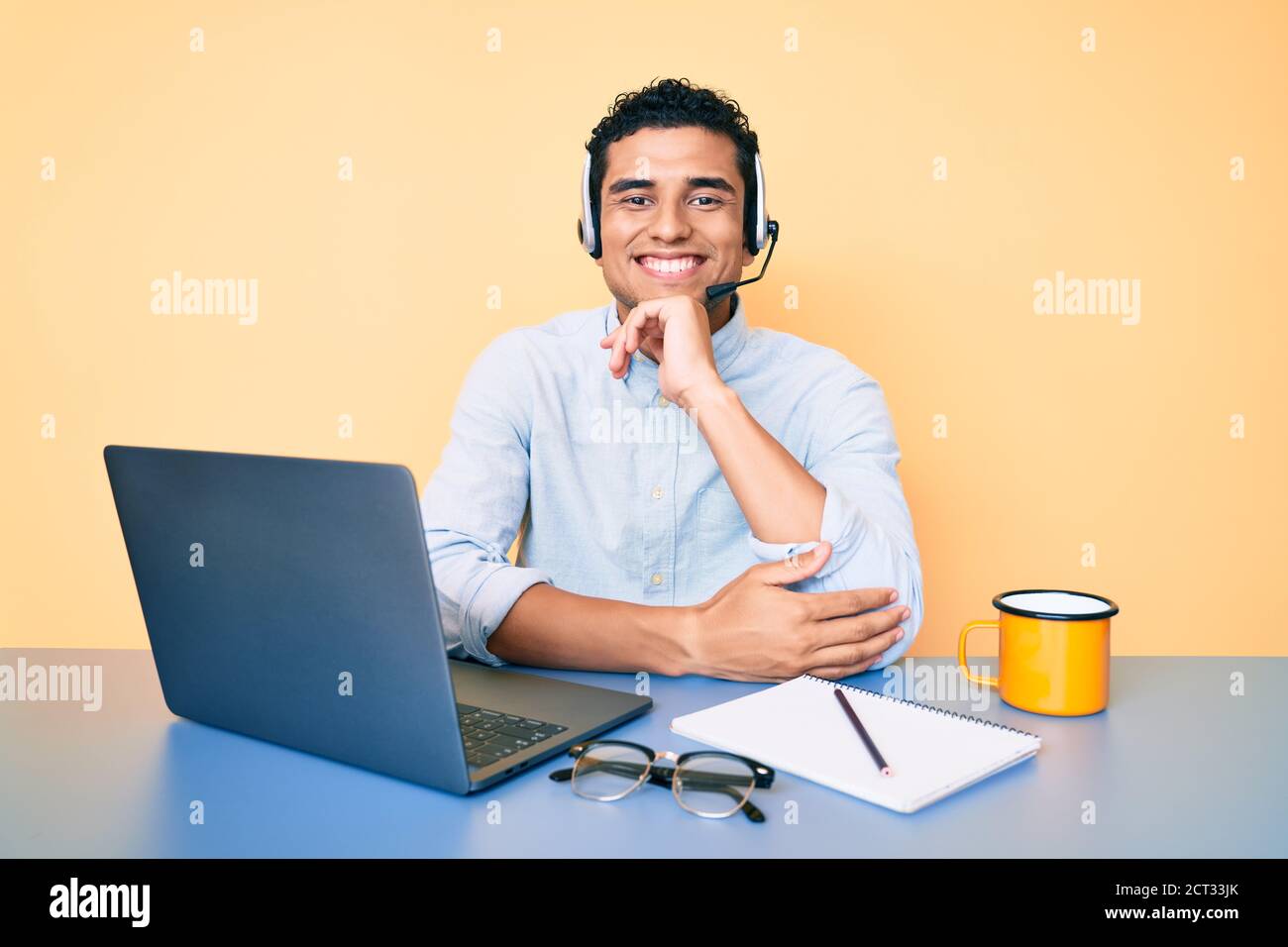 Young handsome hispanic man working at the office wearing operator ...