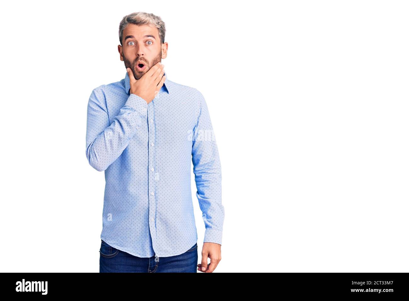 Young handsome blond man wearing elegant shirt looking fascinated with ...