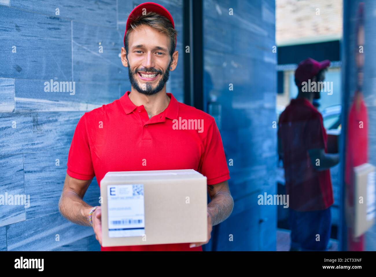 Caucasian delivery man wearing red uniform and delivering parcel Stock ...