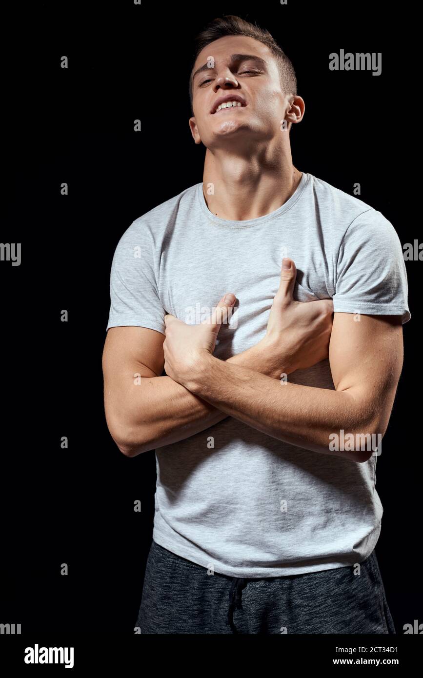 handsome man in white t-shirt on black background inflated arm muscles ...