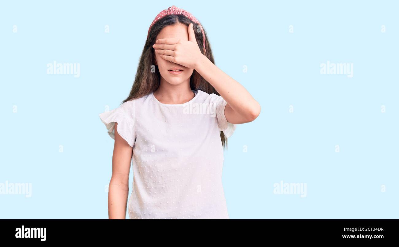 Cute hispanic child girl wearing casual white tshirt covering eyes with ...