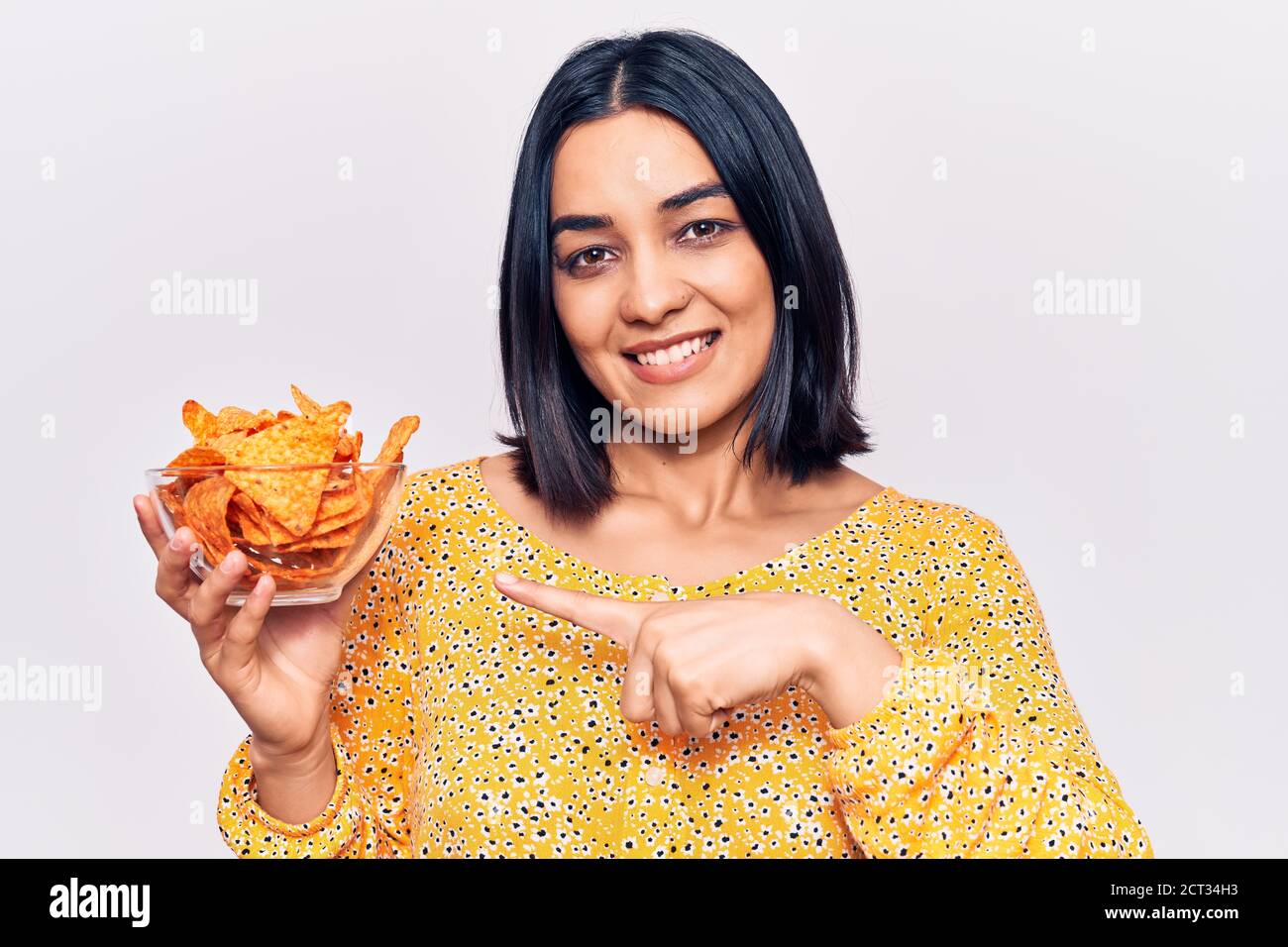 Young beautiful latin woman holding nachos potato chips smiling happy ...