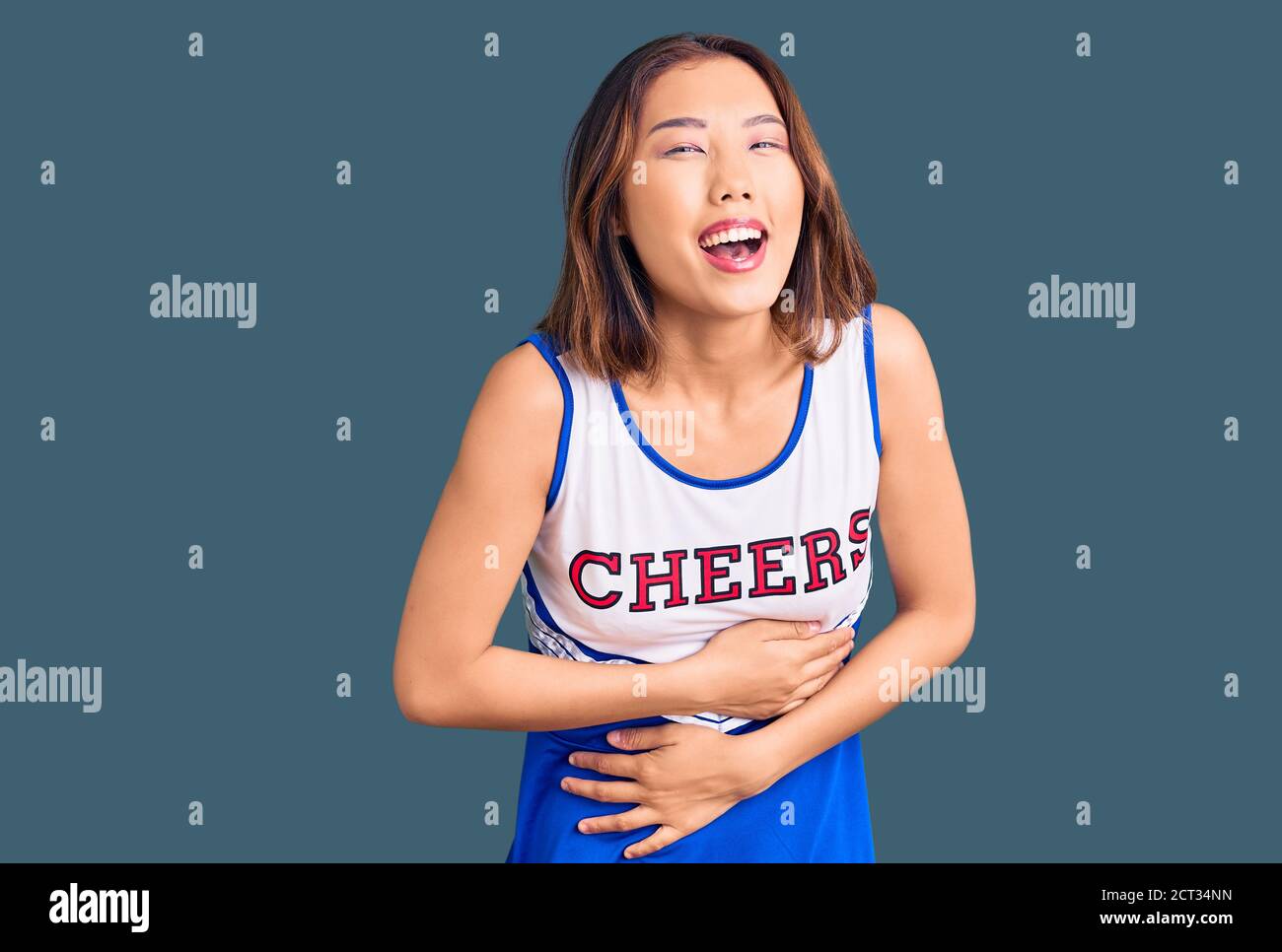Young beautiful chinese girl wearing cheerleader uniform smiling and ...