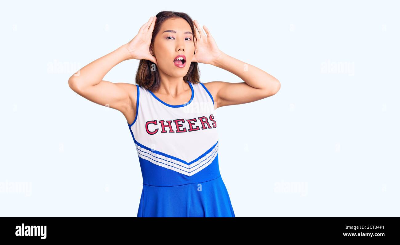 Young beautiful chinese girl wearing cheerleader uniform smiling ...