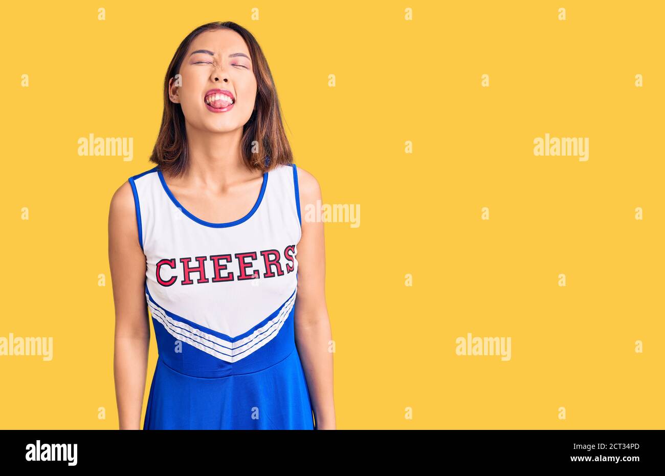 Young beautiful chinese girl wearing cheerleader uniform sticking ...