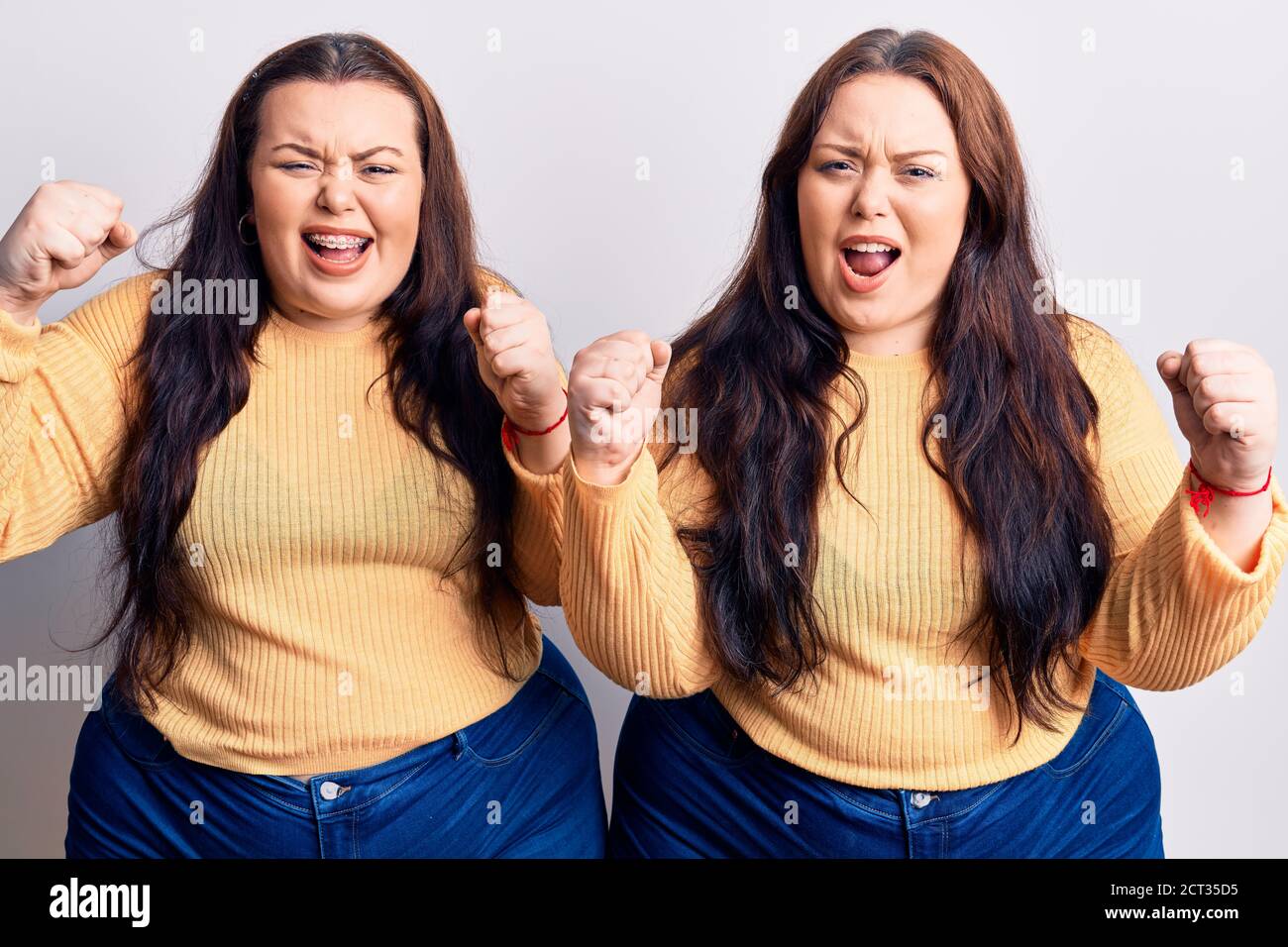 Young plus size twins wearing casual clothes angry and mad raising ...