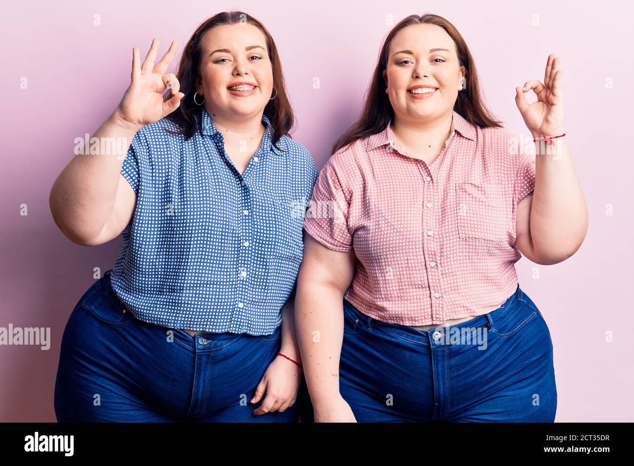 Young plus size twins wearing casual clothes smiling positive doing ok ...