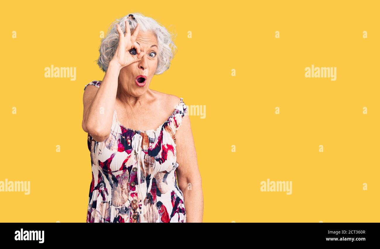 Senior grey-haired woman wearing casual clothes doing ok gesture ...