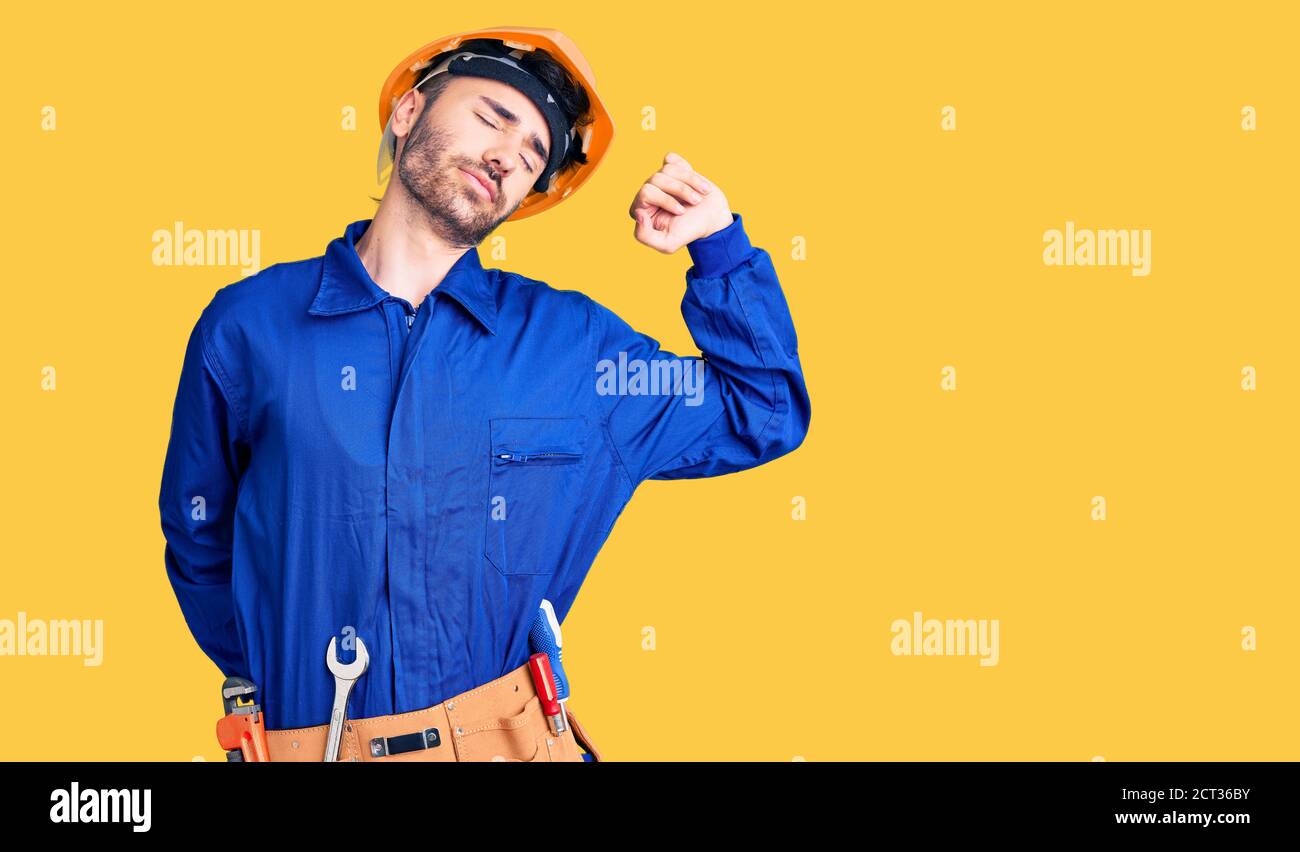 Young hispanic man wearing worker uniform stretching back, tired and ...