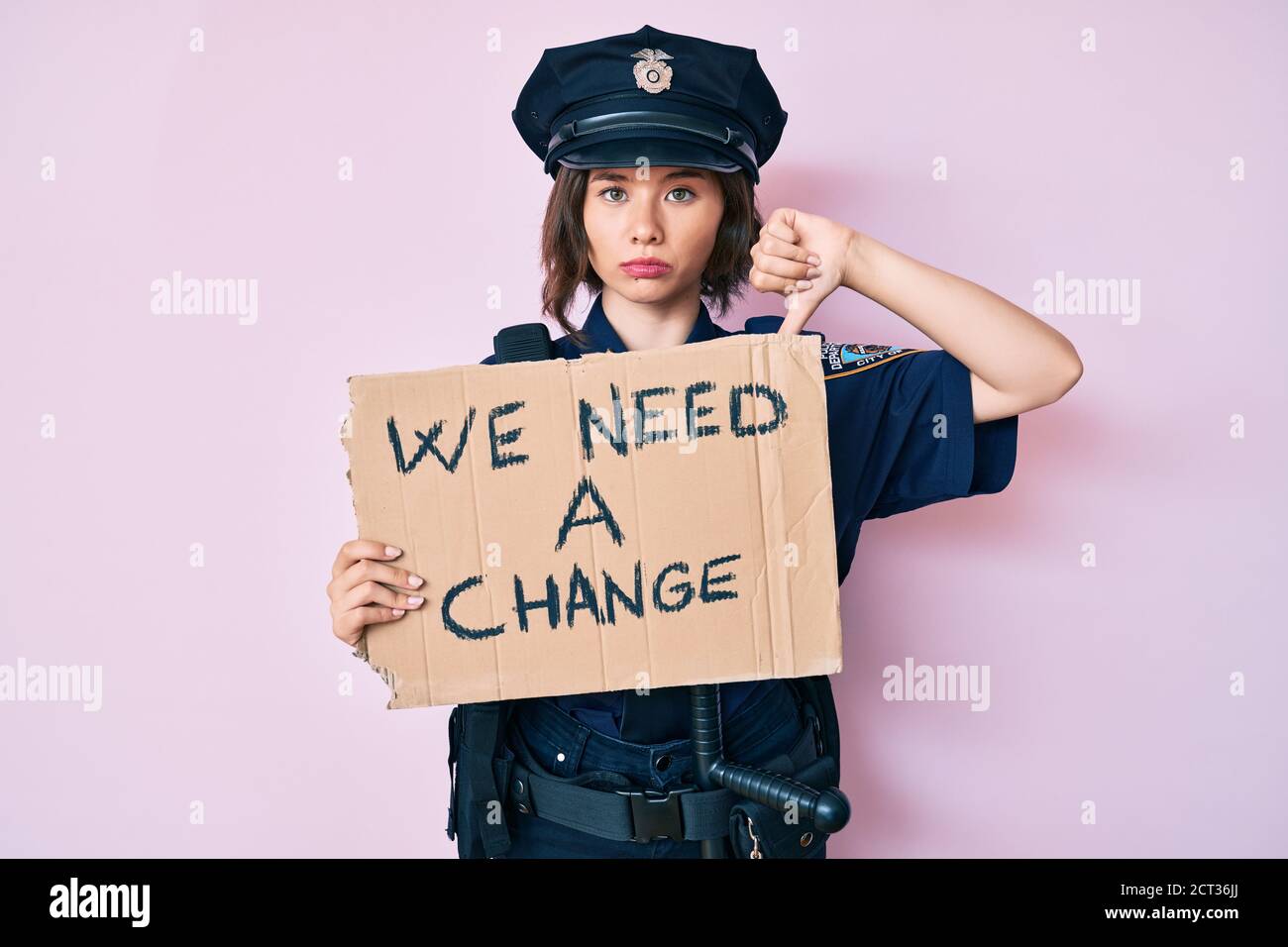 Young beautiful woman wearing police uniform holding we need a change ...