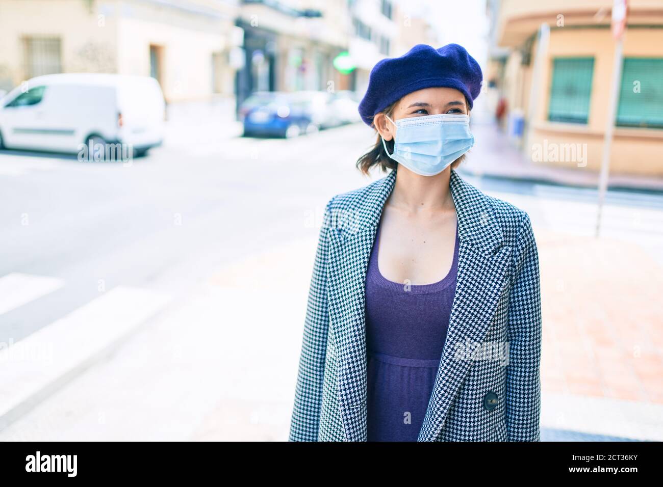 Young beautiful girl smiling happy wearing beret and medical mask walking at street of city ...