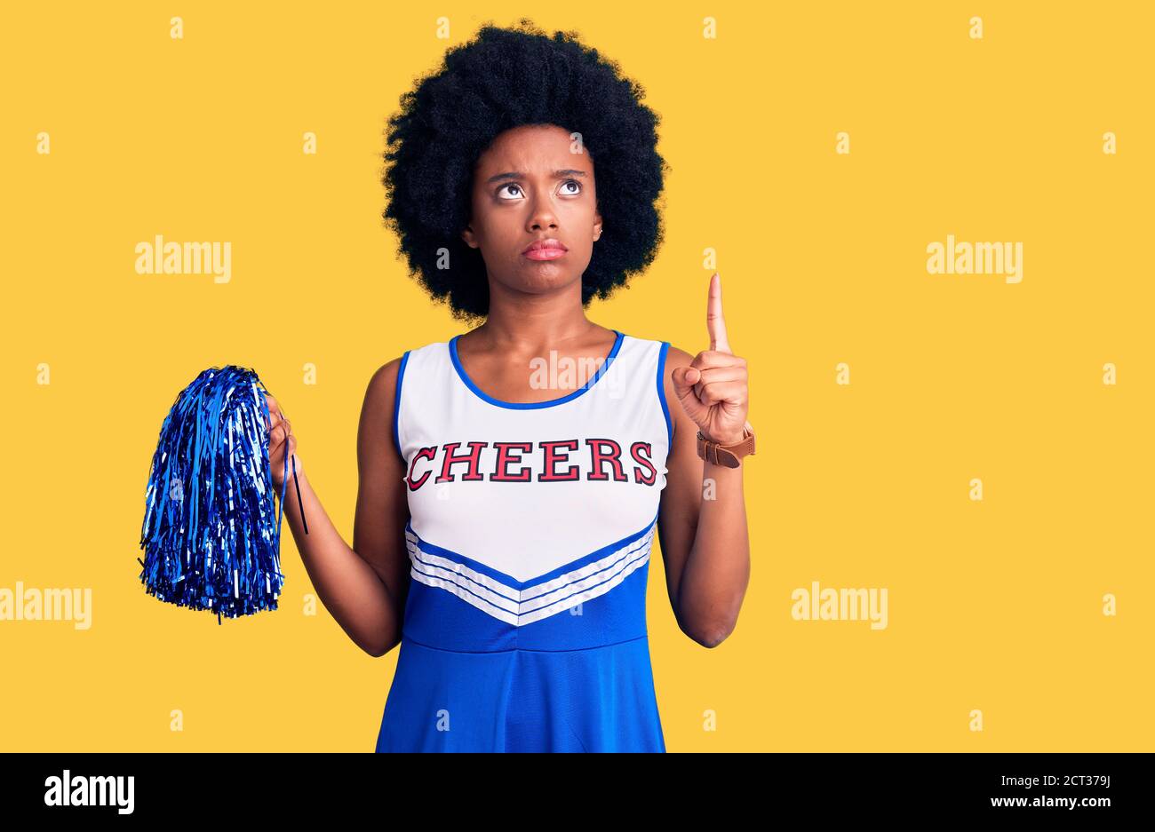 Young african american woman wearing cheerleader uniform holding pompom ...