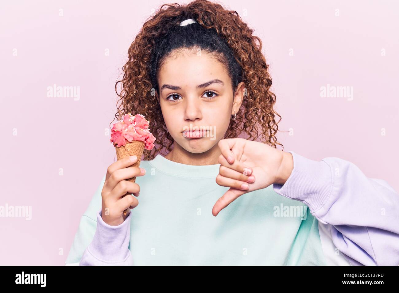 Beautiful kid girl with curly hair holding ice cream with angry face ...