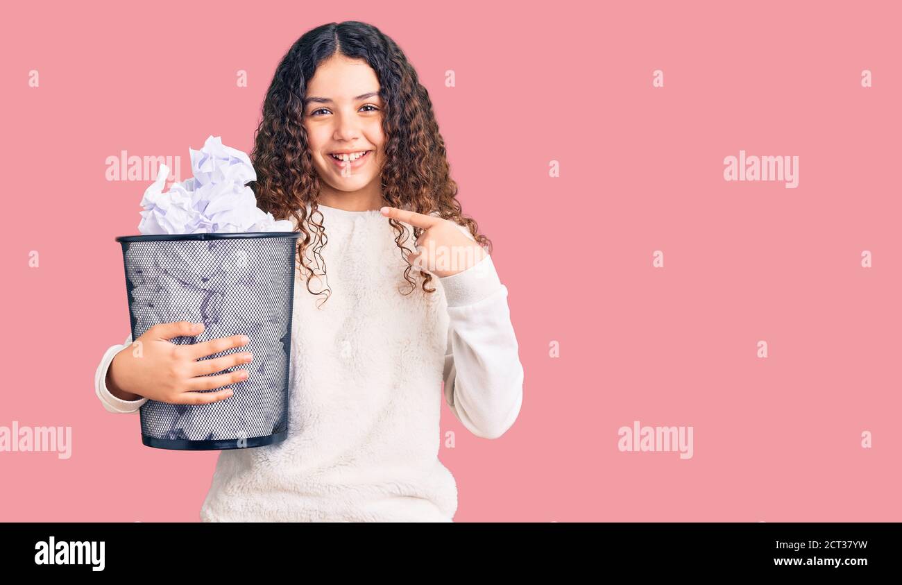 Beautiful kid girl with curly hair holding paper bin full of crumpled ...