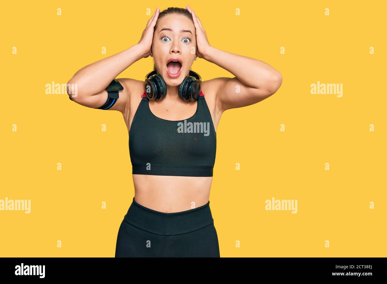 Beautiful blonde woman wearing gym clothes and using headphones crazy ...